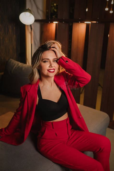 A Beautiful Girl Dressed In A Red Formal Suit Posing In A Modern