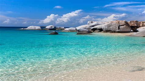 Download A Beach With Clear Water And Rocks Wallpaper