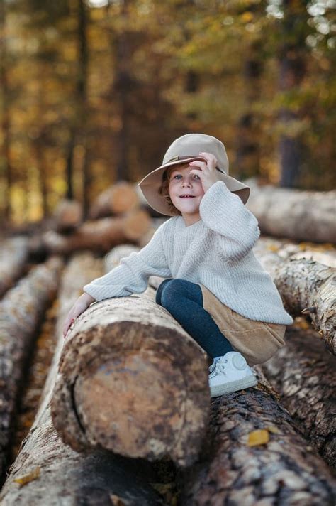 Cute Girl With Hat Sitting On Logs In The Middle Autumn Forest Having