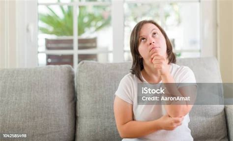 다운 증후군 여자 질문에 대 한 홈 심각한 얼굴 생각에 소파에 앉아 매우 혼란 스 러 워 아이디어 가정 생활에 대한 스톡 사진 및 기타 이미지 Istock