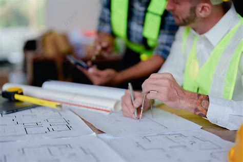 Diverse Engineers Plan And Estimate Building Costs Blueprint Drawings