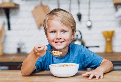 Niño Comiendo Cereales Mientras Mira A La Cámara Foto Premium