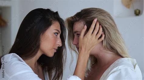 Two Sensual Lesbians Are Sitting On The Bed In Front Of Each Other The