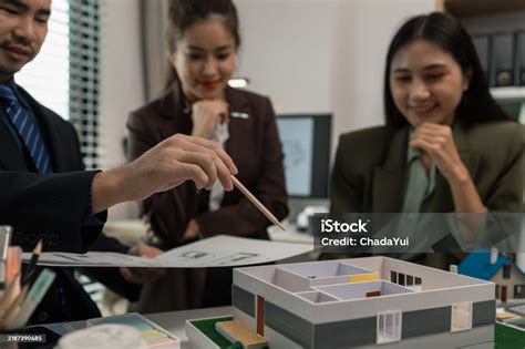 건축가는 사무실에서 엔지니어 및 계약자와 협력하여 첫 번째 초안 계획 책상 위의 청사진 작업장에서 함께 작업하는 청사진의