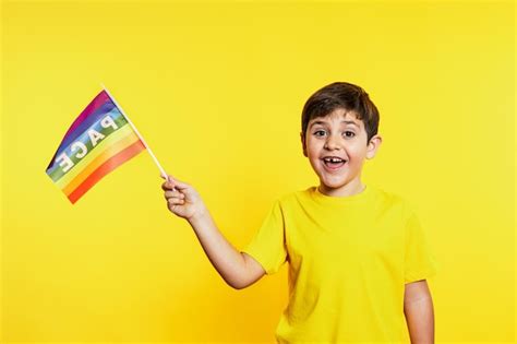 Premium Photo Boy In Yellow Shirt Proudly Waves A Rainbow Peace Flag