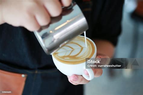 라떼 아트를 만들기 위해 커피잔에 따뜻한 우유를 붓는 바리스타의 손 커피숍에서 커피를 마시는 바리스타의 다재다능함 뜨겁고 차가운 음료의 전문가이며 고객에게 봉사할 준비가