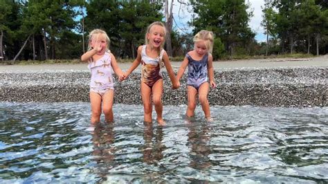Triplet Sisters Swim In Sea Water On A Pebble Beach Pine Trees Can Be