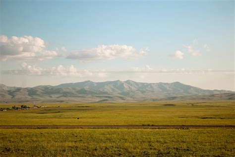 Landscape Of A Flat Grass Field And Mountains In The Horizon · Free