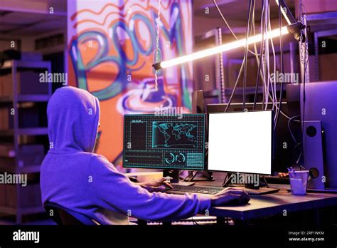 Criminal In Hood Coding Malicious Software On Computer With Empty White Screen And Hacking