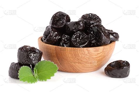 带薄荷叶的干梅子或西梅子放在木碗里，孤立在白色背景上