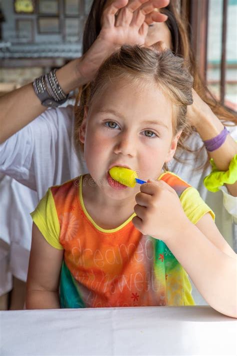 Una NiÃ±ita Linda Comiendo Helado Y Mirando Sentada En Las Piernas De Su Madre Foto De Archivo