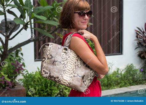 Fashionable Woman In Red Dress Holding Leather Snakeskin Python Bag