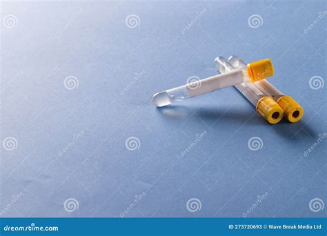 Three Sample Tubes Of Clear Fluid With Yellow Lids On Blue Background