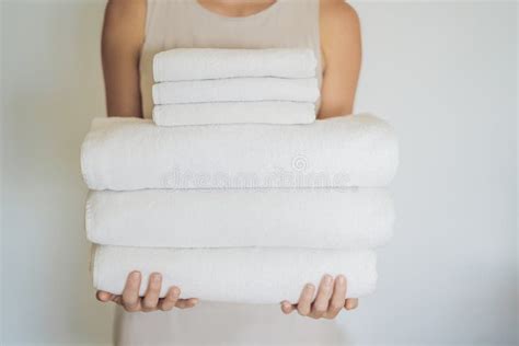A Woman Is Holding A Stack Of White Towels Concept Of Service I Stock