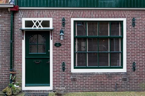 典型的なオランダの田舎の正面玄関と窓。ヴィンテージヨーロッパの村の家のファサード。美しいレトロな玄関ドアオランダ。 プレミアム写真