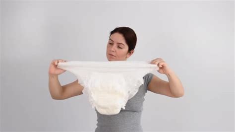 A Caucasian Woman Holds An Adult Diaper And Checks Its Strength On A
