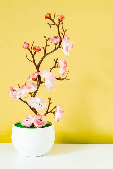 Artificial Japanese Sakura Plant In A White Pot In Front Of A Green