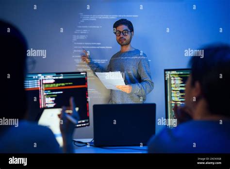 Asian Developer Leads Present Code Review Session Pointing At Code Projected On The Wall With