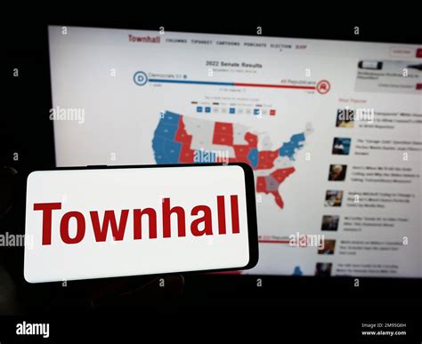 Person Holding Mobile Phone With Logo Of American Conservative News