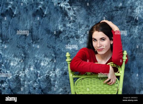 Resting On A Chair Turned Backwards This Female Teen Smiles With Her Eyes As She Leans Across