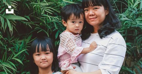 흰색과 분홍색 꽃 무늬 드레스를 입은 소녀를 들고 파란색 민소매 셔츠를 입은 여자 사진 Unsplash의 무료 초상 이미지