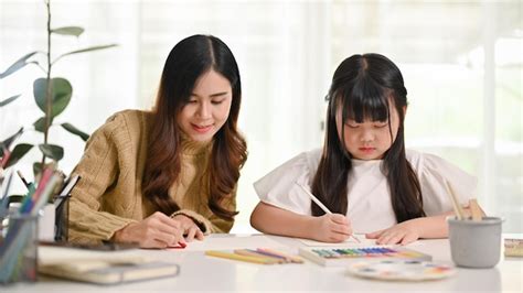 Atractiva Hermana Asiática Ayudando A Su Hermana Pequeña A Dibujar Y