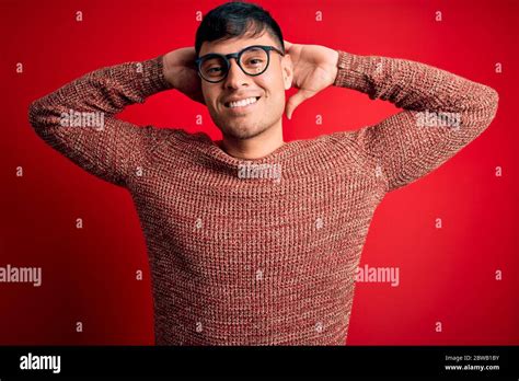 Young Handsome Hispanic Man Wearing Nerd Glasses Over Red Background Relaxing And Stretching