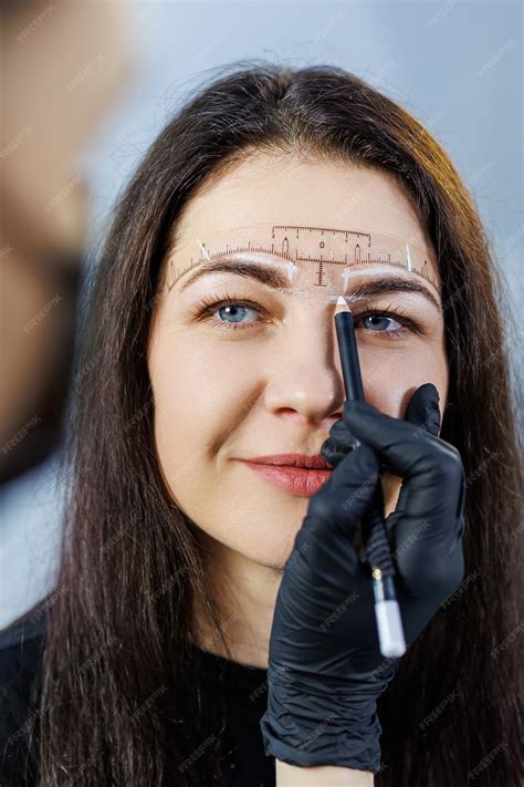 A Permanent Makeup Artist Marks A Womans Eyebrows With A Pencil