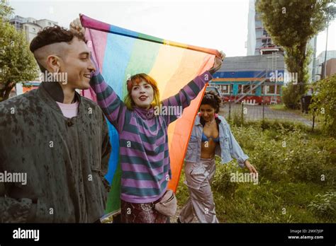 Woman Holding Lgbt Flag While Walking With Non Binary Friends At Park