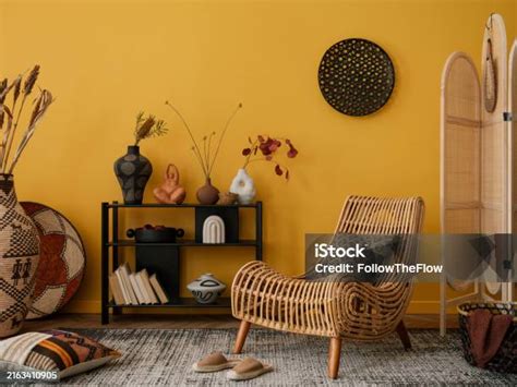 세련된 안락 의자 나무 칸막이 벽 검은 색 찬장 화려한 베개 슬리퍼 및 개인 액세서리가있는 따뜻한 거실 인테리어의 창의적인 구성 가정 장식 템플렛 0명에 대한 스톡 사진 및