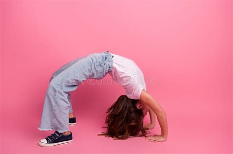 Young Girl Performs A Backbend Pose Against A Vibrant Pink Background Showcasing Flexibility And