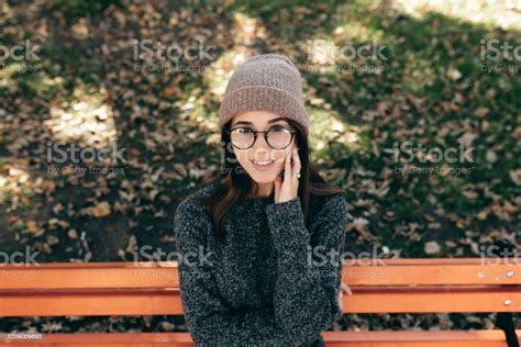 투명 한 안경 스웨터와 모자를 입고 미소 아름 다운 젊은 갈색 머리 여자의 상단 보기 이미지입니다 예쁜 여성 앉아서 공원에서 벤치에 휴식 가을에 대한 스톡 사진 및 기타