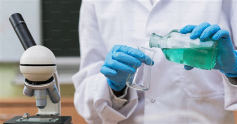 연구 작업 중 실험실에서 한 플라스크에서 다른 플라스크로 물질을 붓는 과학자 사진 Unsplash의 화학자 이미지