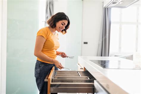 Premium Photo Smiling Middle Eastern Female Tidying Up Cutlery In Kitchen Drawer Side View