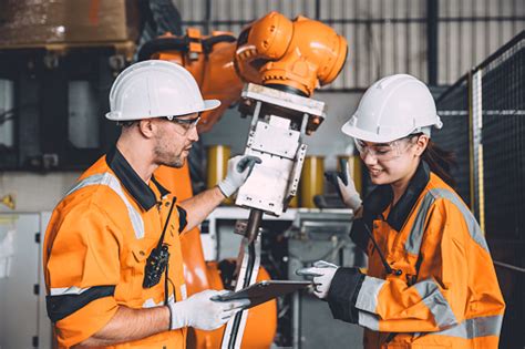 자동화 공장에서 일하는 엔지니어 팀 서비스 로봇 용접 안전복을 입은 사람들은 로봇 팔 소프트웨어 프로그래밍 또는 자동화 제조 산업 기술의 부품 교체 작업을 합니다 20 24
